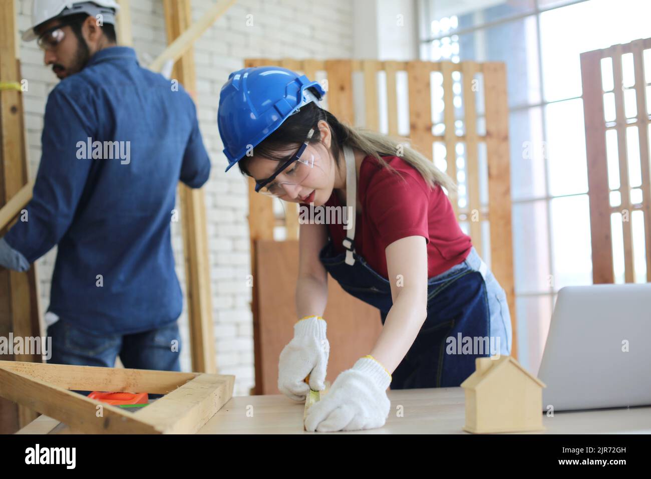 Side view portrait of modern female carpenter measuring wooden part ...