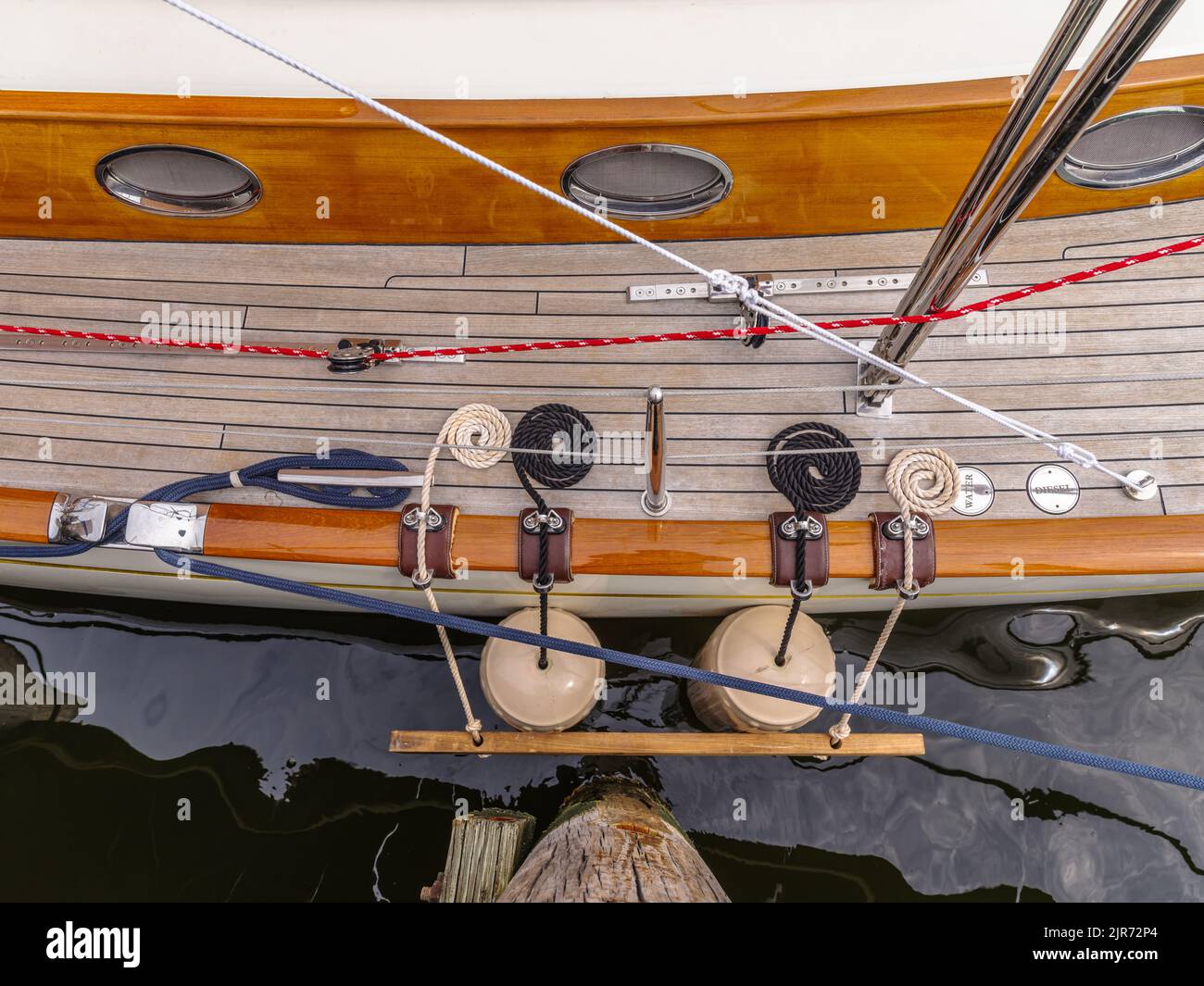 Starboard rail of luxury sailing yacht, its fender and a pier piling ...