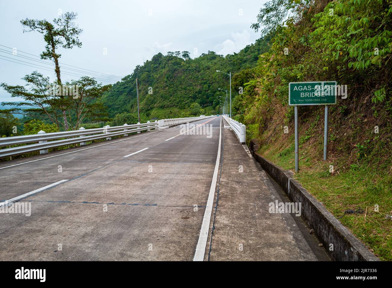 An isolated highway in Leyte, Philippines, with green lush trees in the ...
