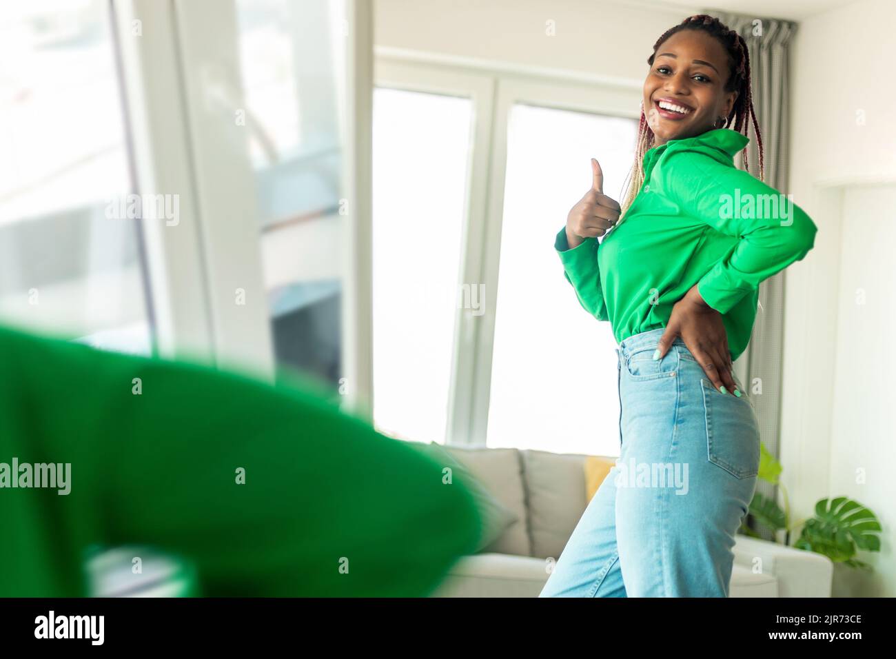 Cheerful fit black lady looking at her reflection in mirror and showing ...