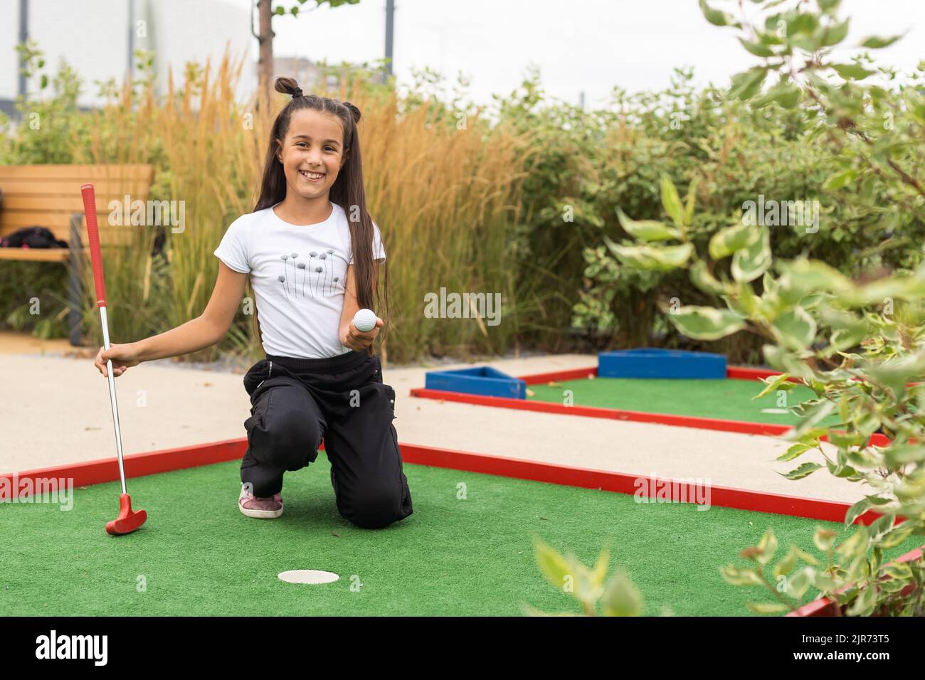 Cute preschool girl playing mini golf with family. Happy toddler child ...