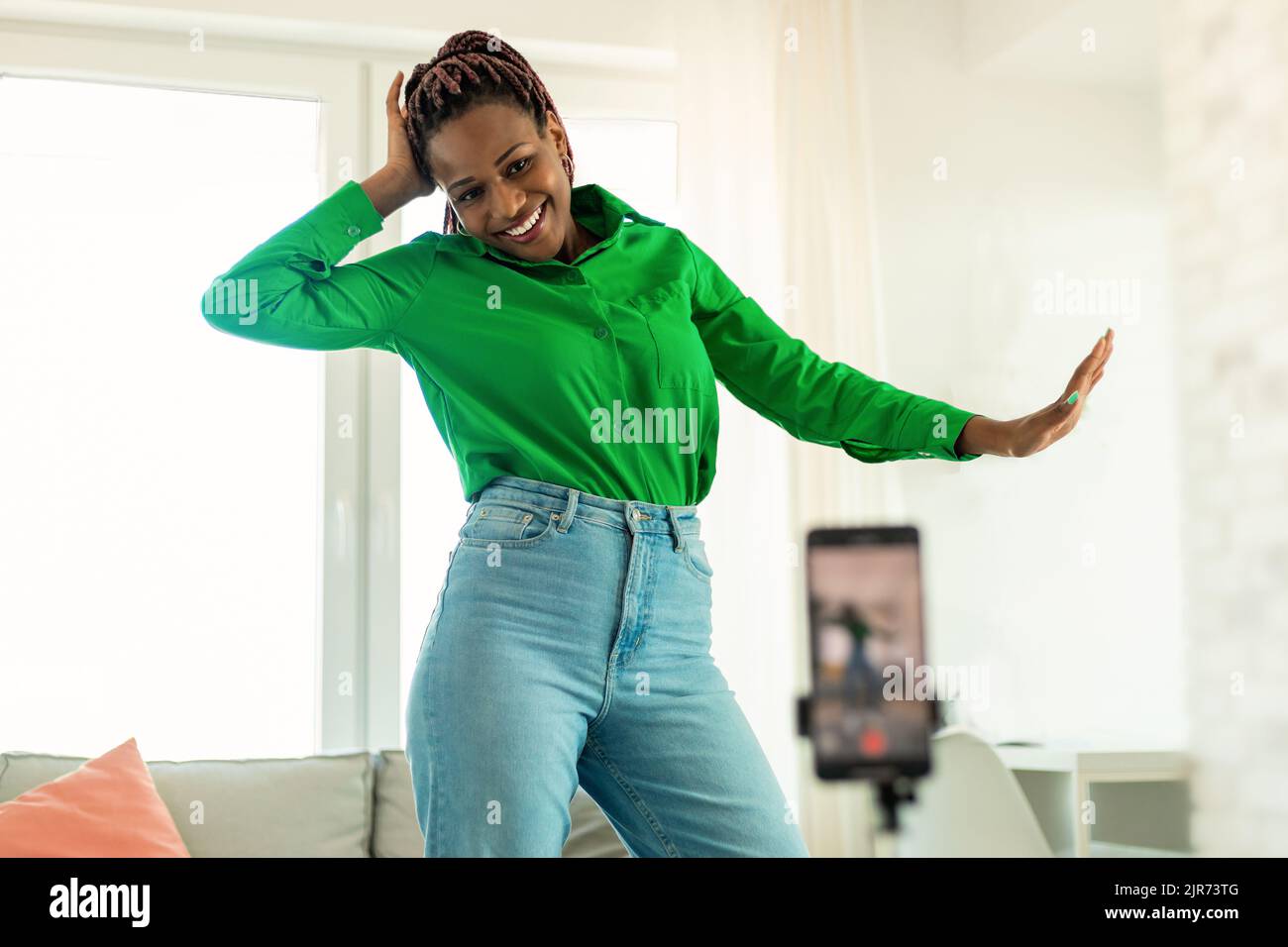 Black female influencer recording video on smartphone, dancing on ...