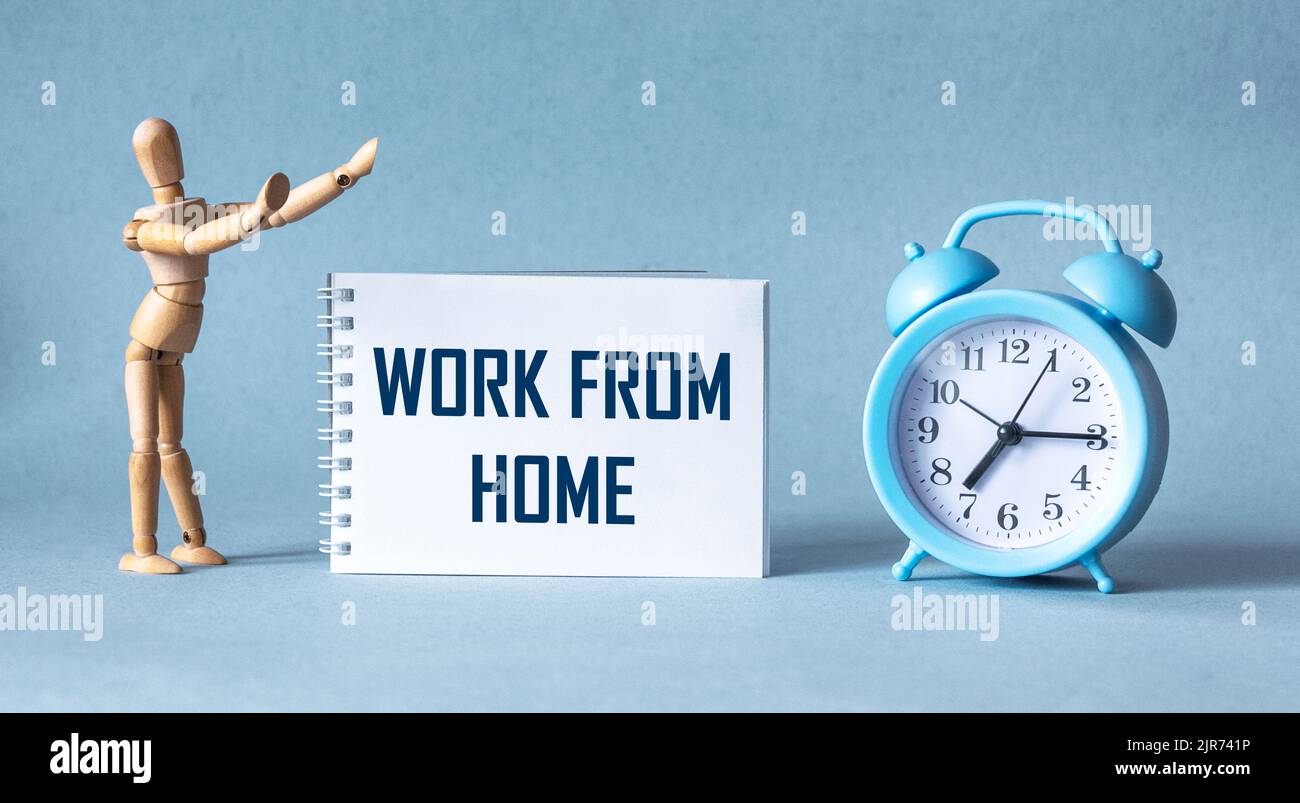 Work from home message on notepad and blue background. wooden doll and ...