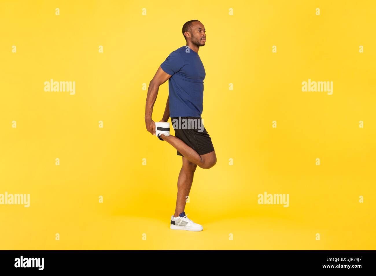Sporty African American Male Exercising Stretching Leg Over Yellow ...