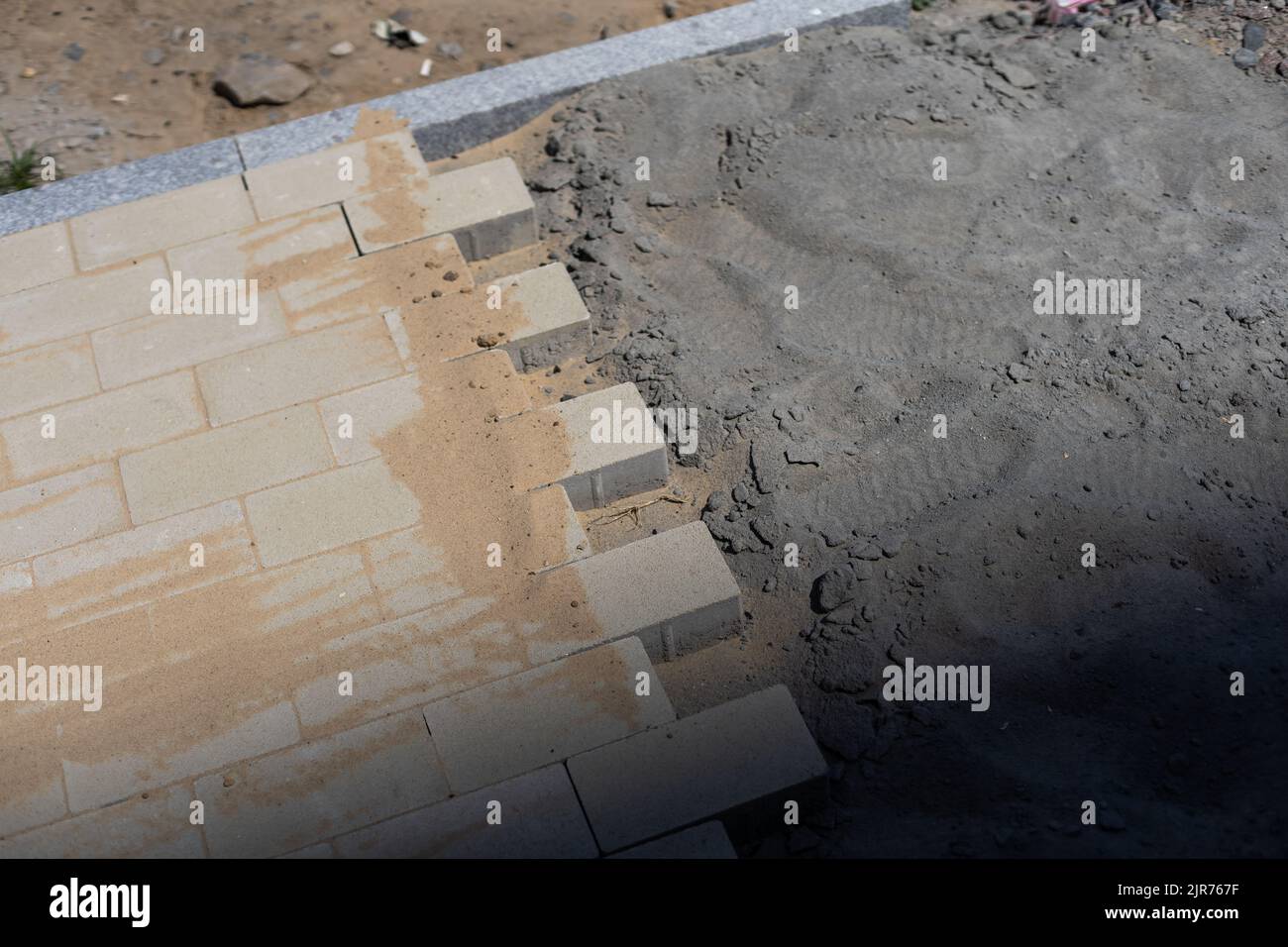 Stone blocks laying is on sand base. Sidewalk device Stock Photo - Alamy
