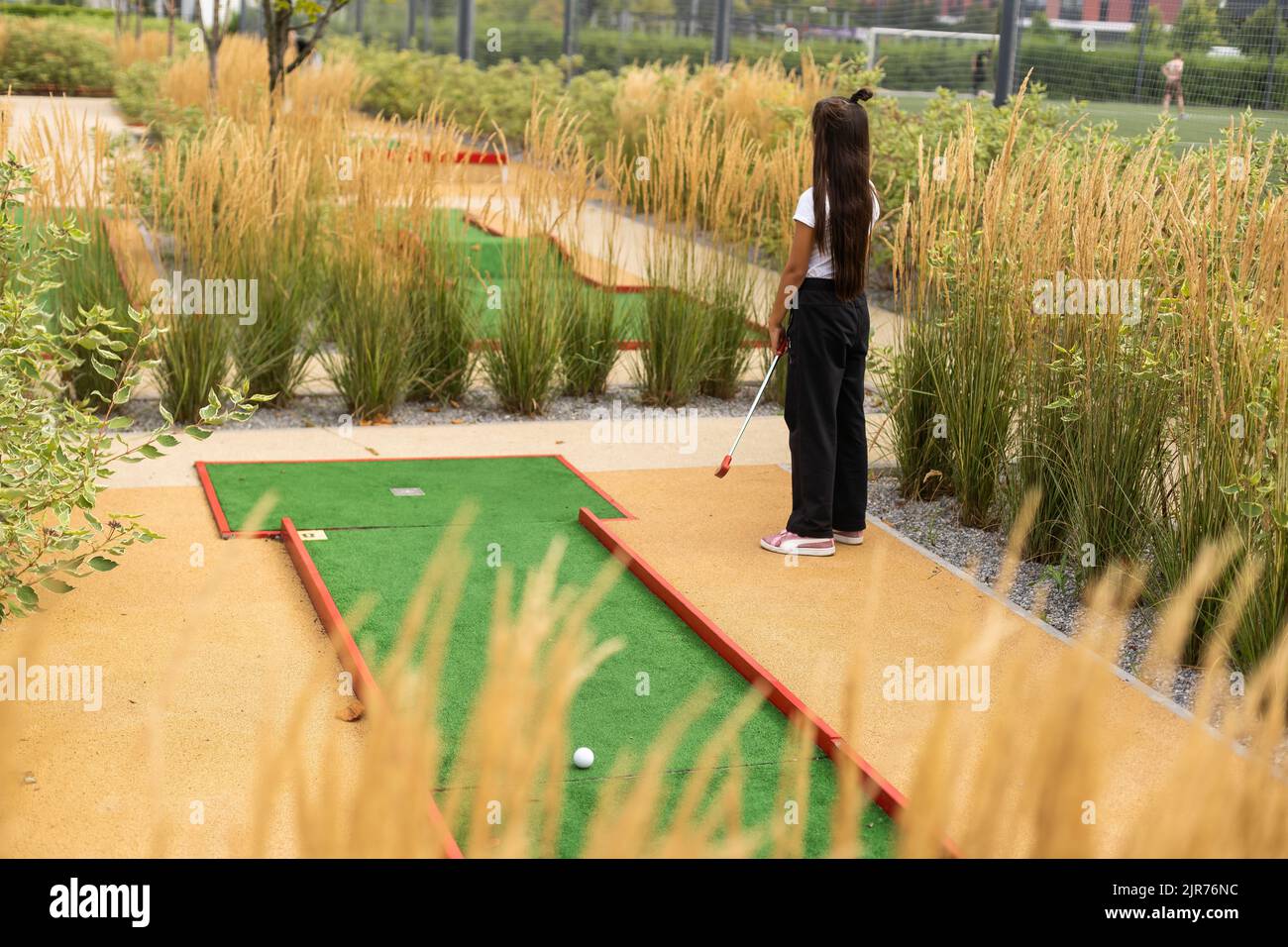 Miniature golf outdoor. Little caucasian girl golfing in the mini golf ...