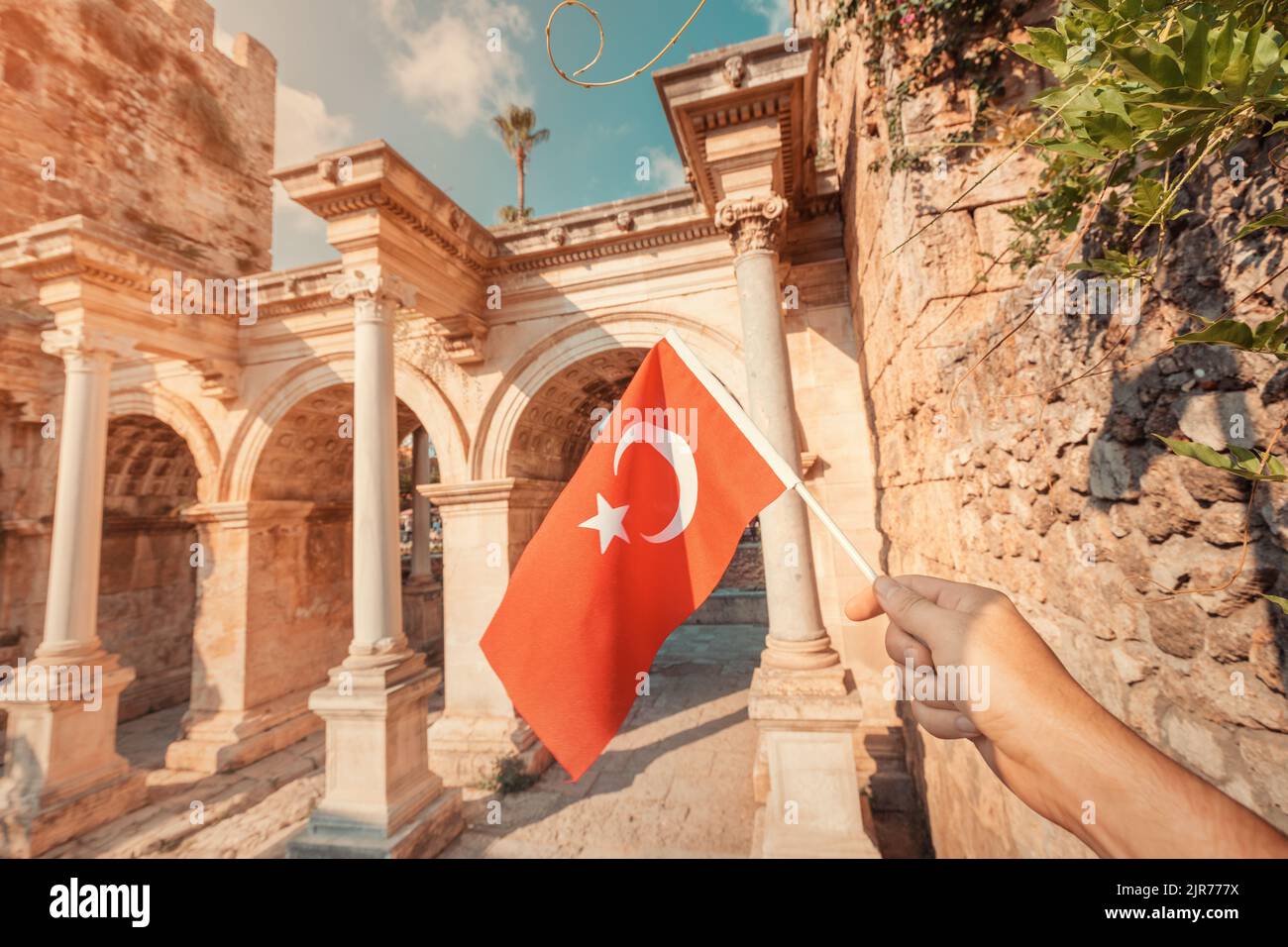 Turkish Flag in hand and famous gate or Hadrian arch in Antalya. Travel ...