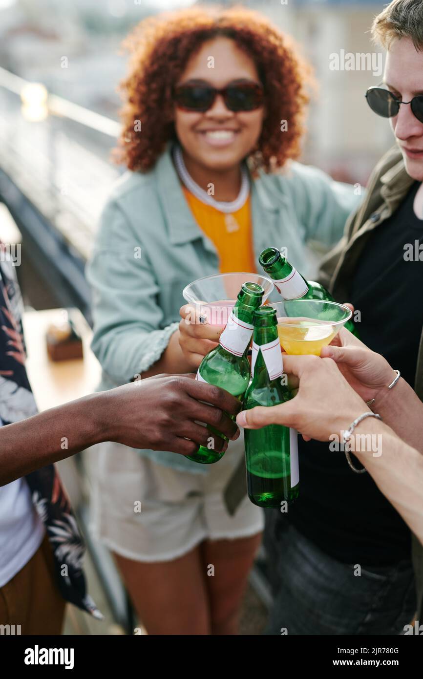 Young cheerful black woman and group of intercultural friends clinking ...