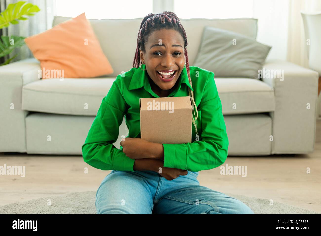 Happy african american lady hugging cardboard parcel, getting online ...