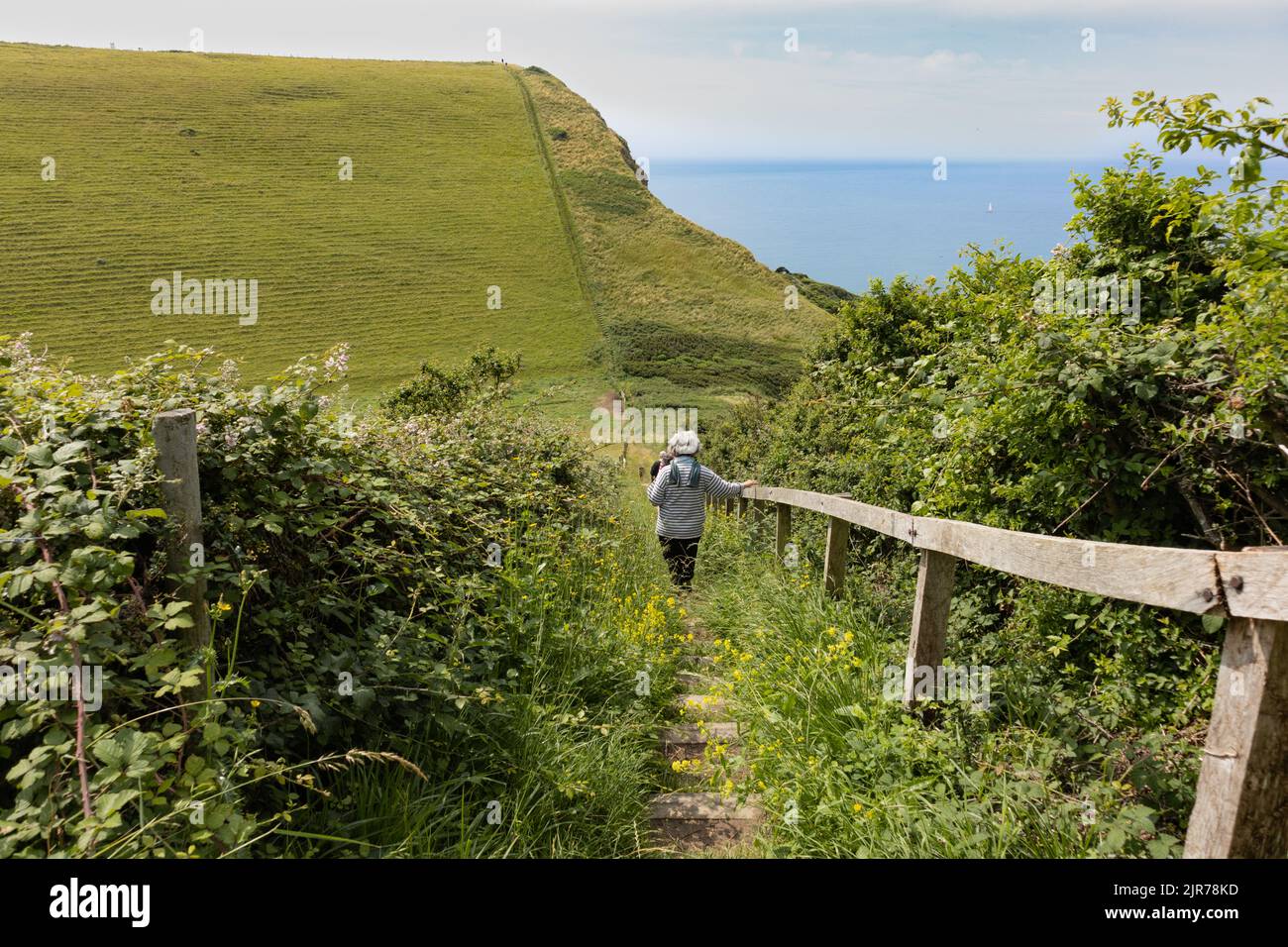 An older hiker walks down a steep set of steps on the South West Coast ...