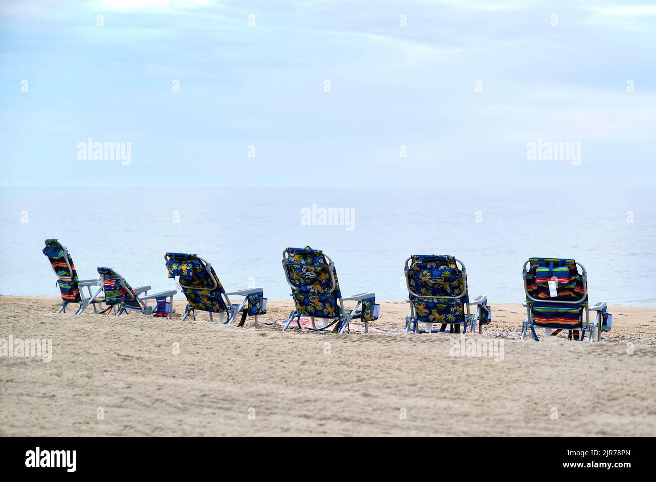 Rear view of a group of six folding beach chairs with no people lined ...