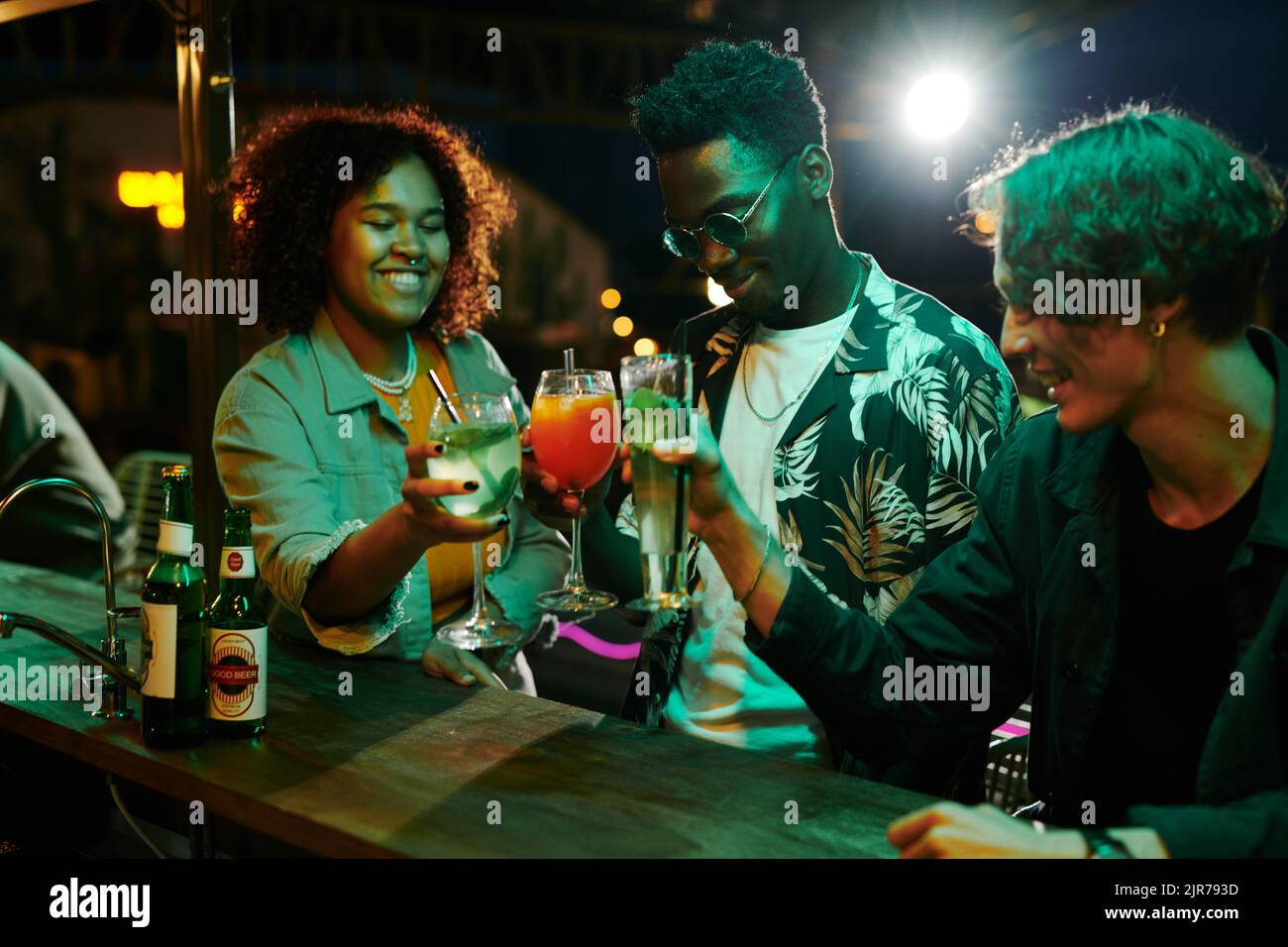 Group of three happy young intercultural people clinking with glasses ...