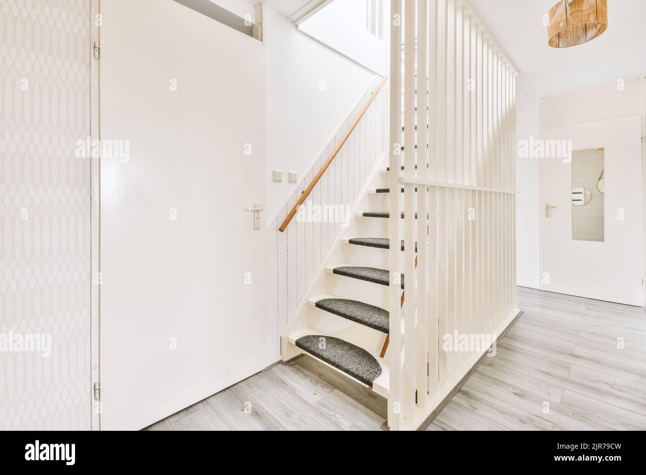 White hallway with wooden stairway leading to second floor of modern ...