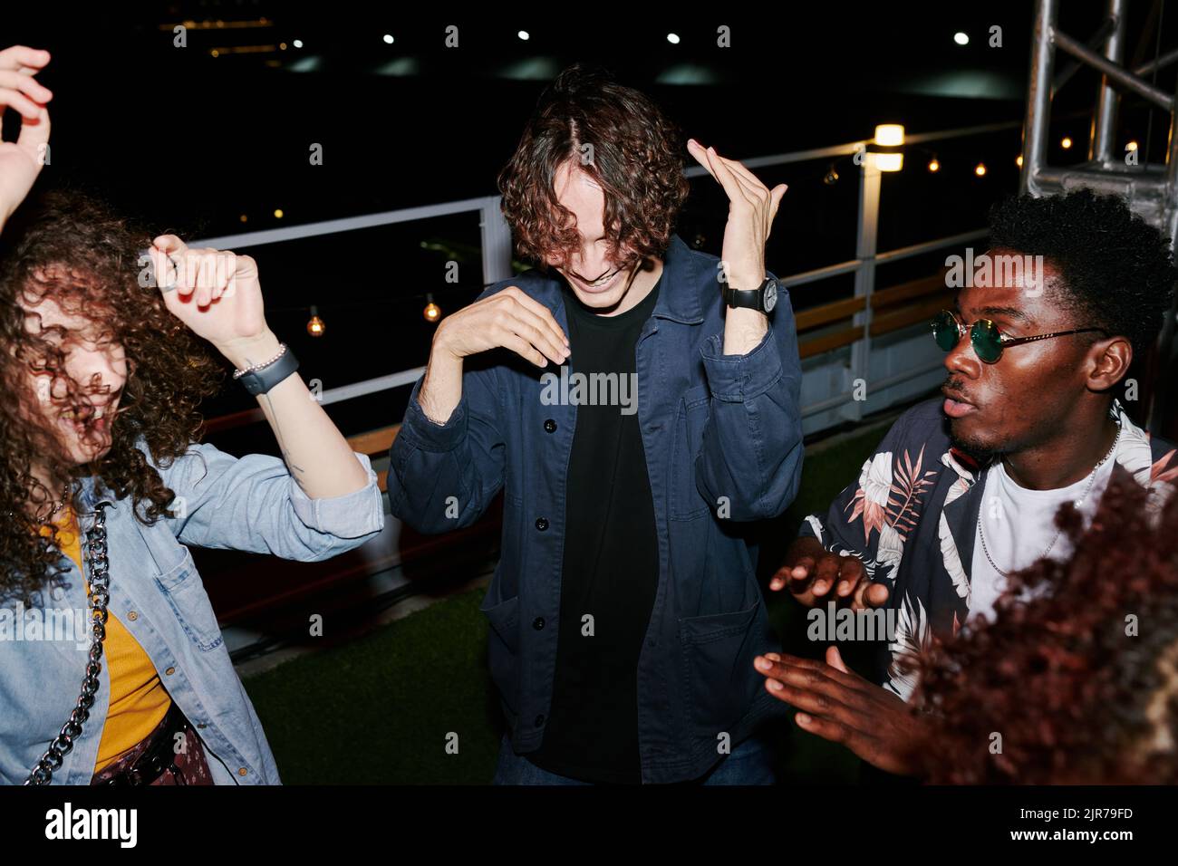 Two young cheerful intercultural couples in stylish casualwear dancing ...
