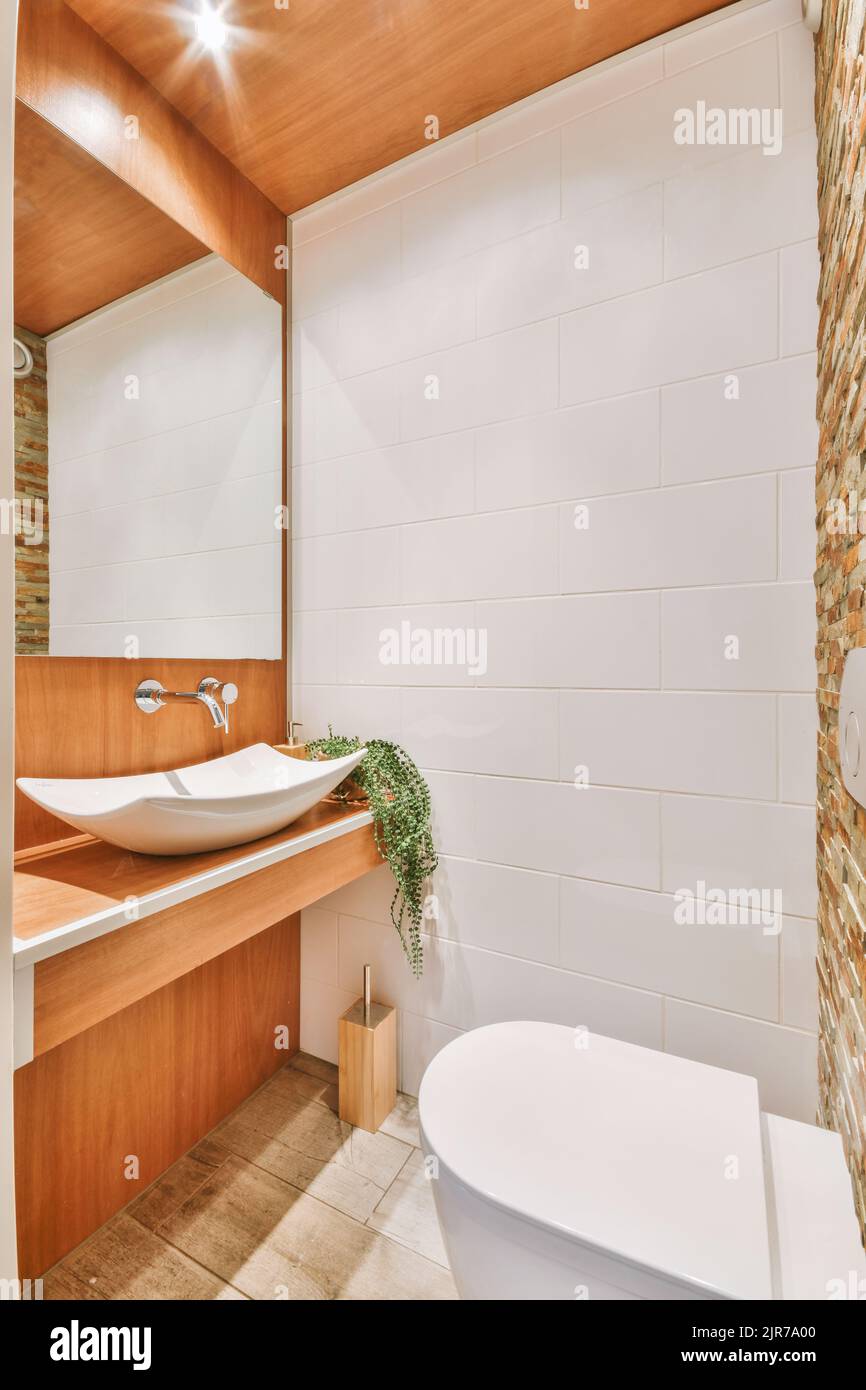 Sink with tap and liquid soap hanging on tiled wall under mirror in ...