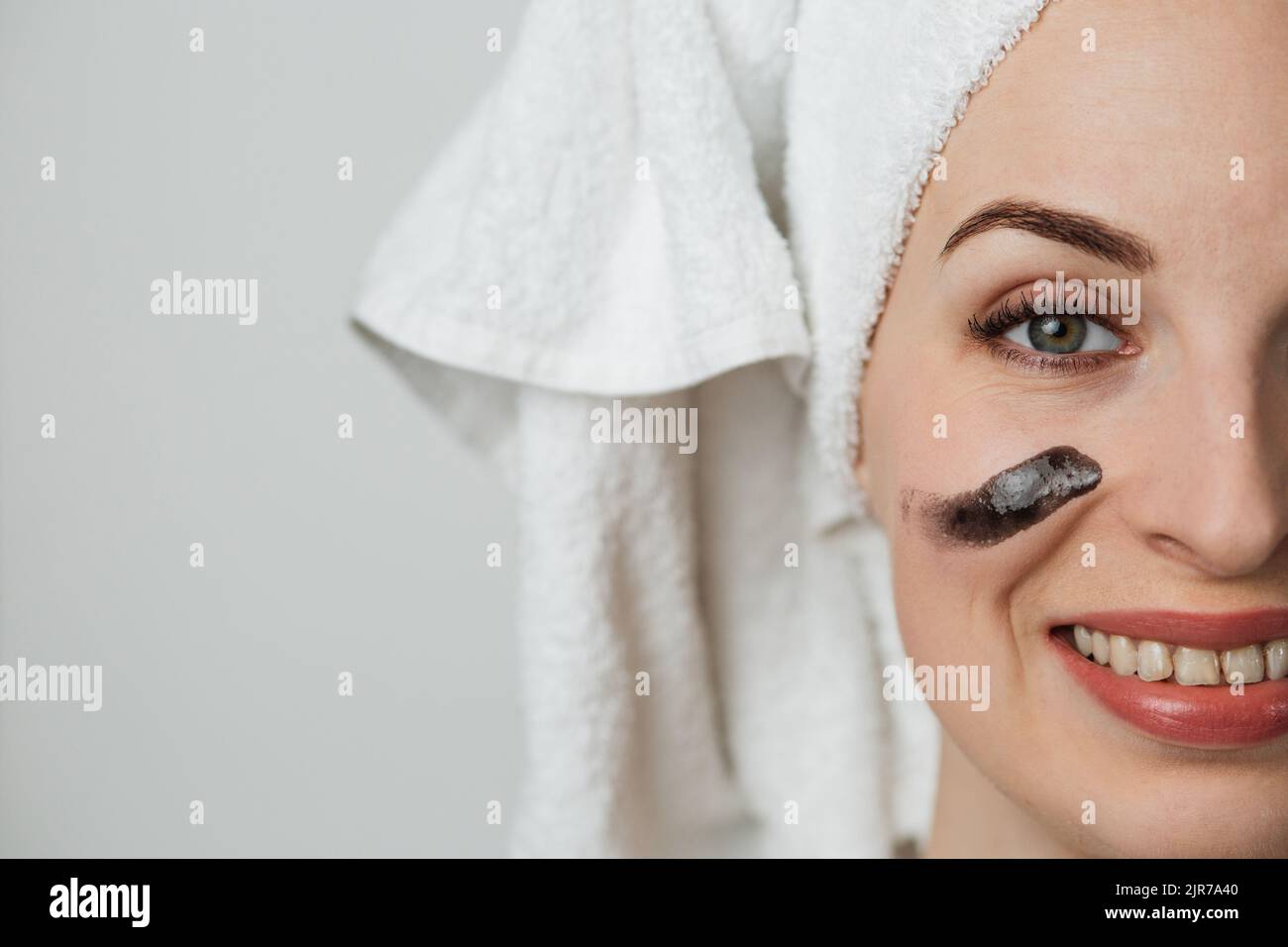 Half face portrait of caucasian young lady applying black face cream ...