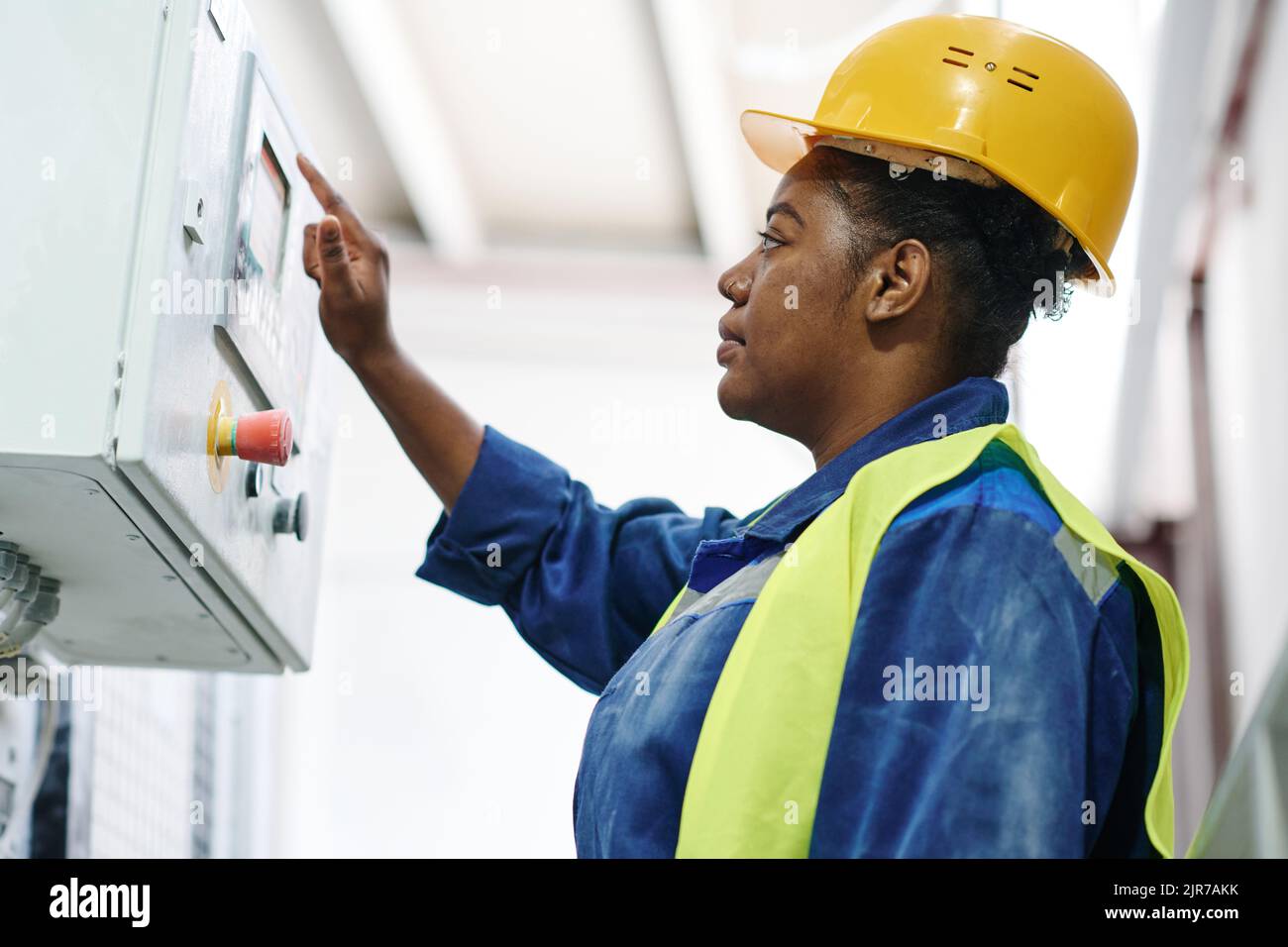 Young serious African American female engineer pressing button on panel ...