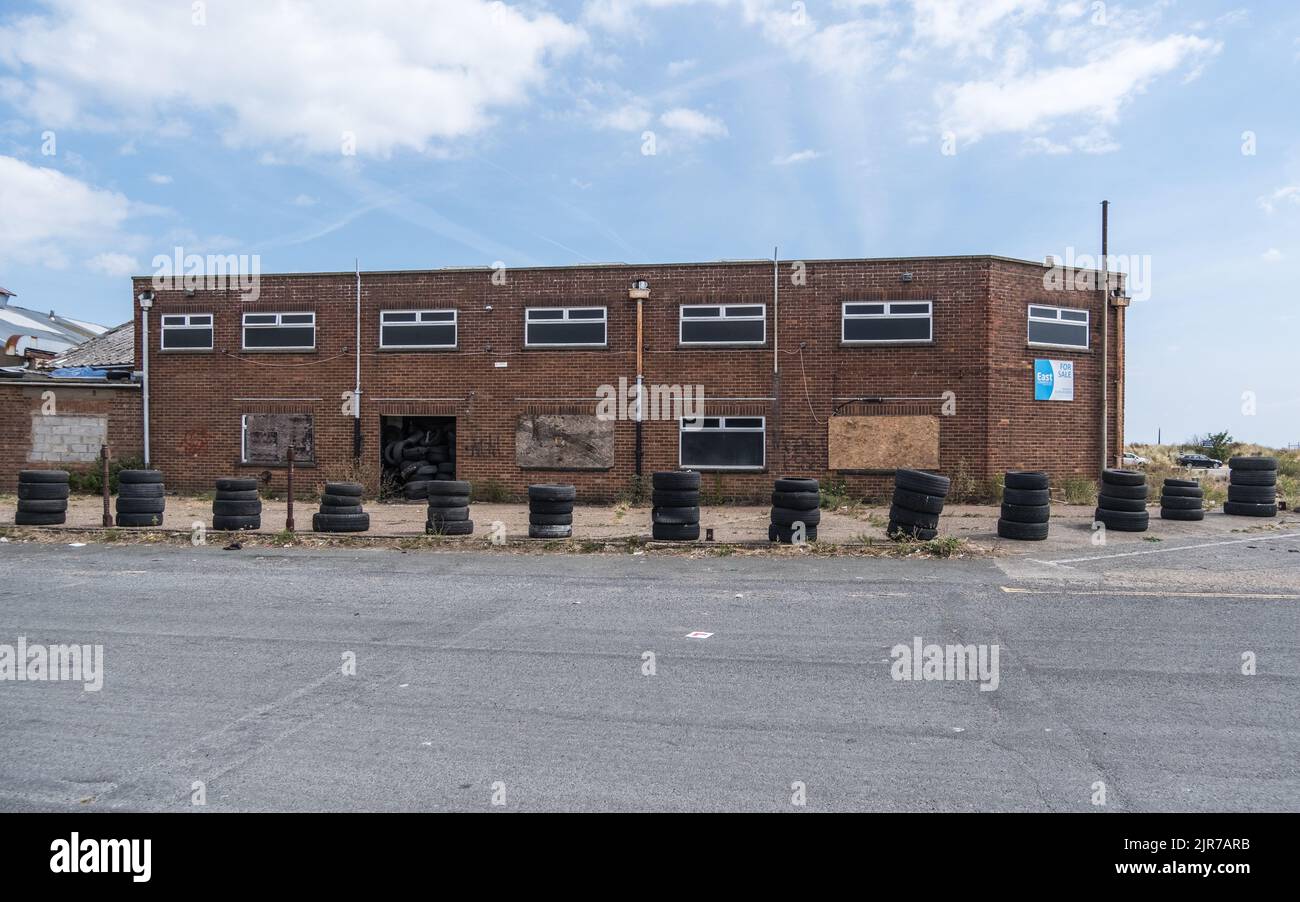 Car tyres stacked in front of abandoned building in an industrial ...