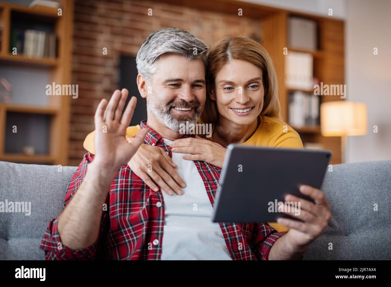 Cheerful mature caucasian female hugging man, waving hand, watching ...