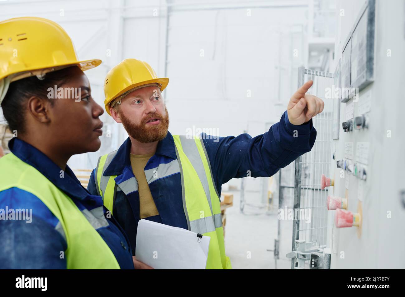 Confident technician or manager explaining female colleague how to ...
