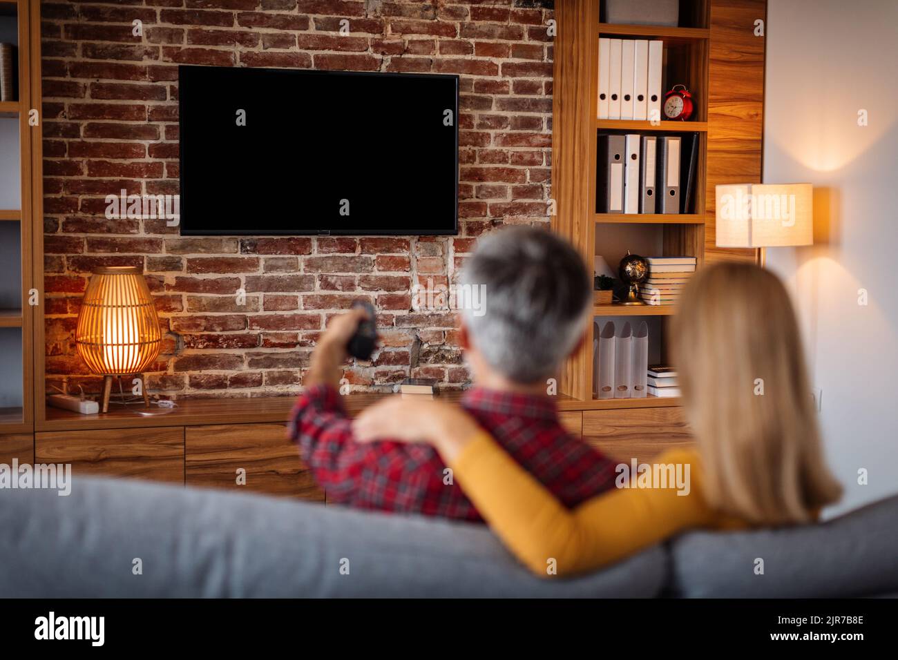 Adult caucasian man with remote control and lady relaxing, watching tv ...