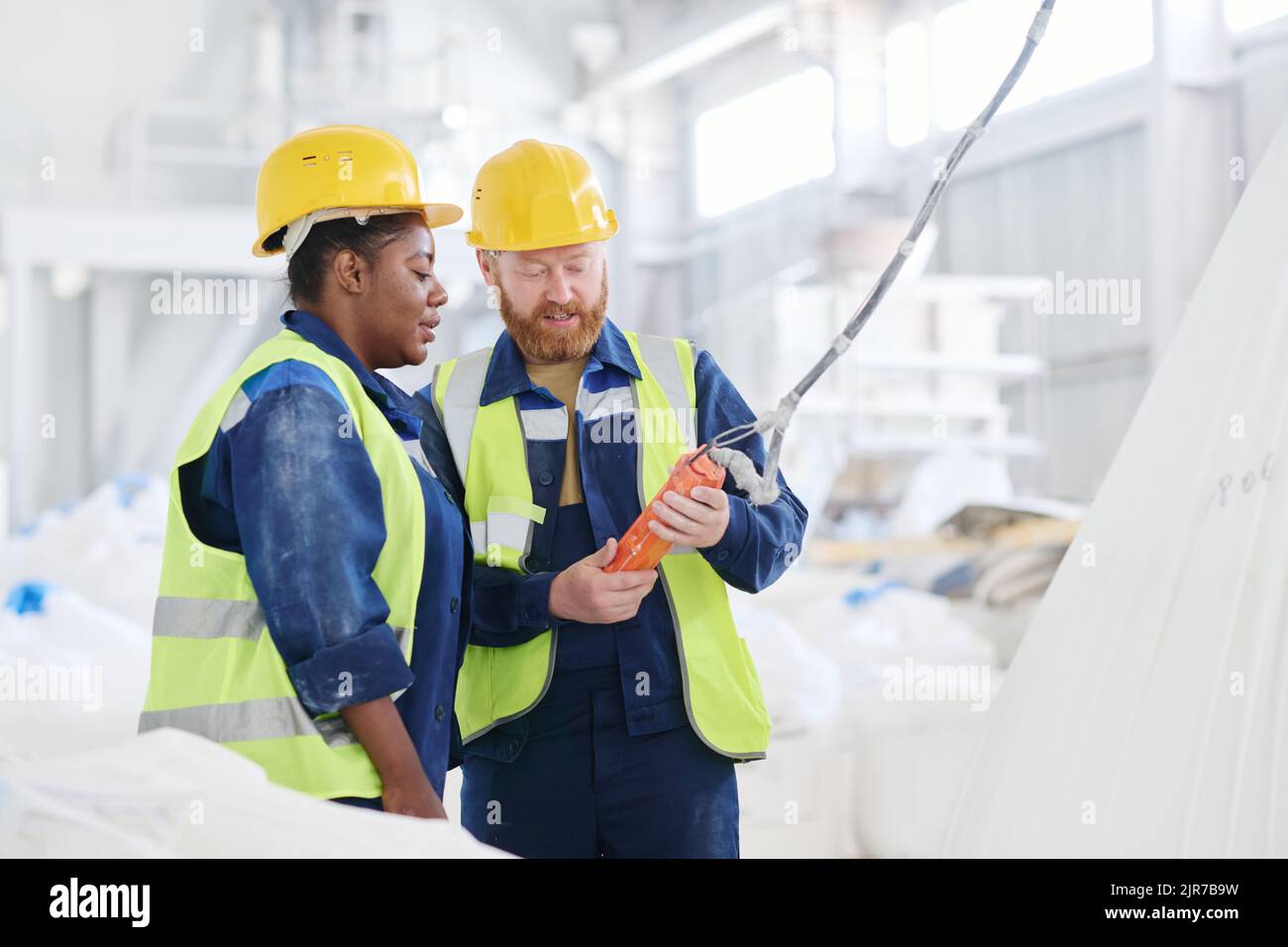 Confident male engineer consulting AFrican American female colleague ...