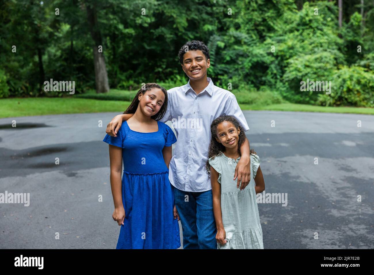 Three siblings standing outside their home hugging and embracing for a ...
