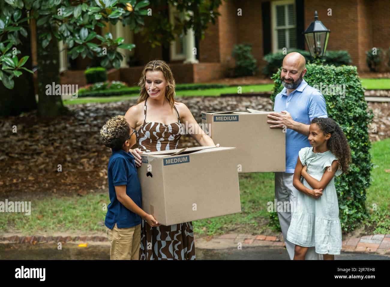 A blended family mom and dad and two young children holding packing ...