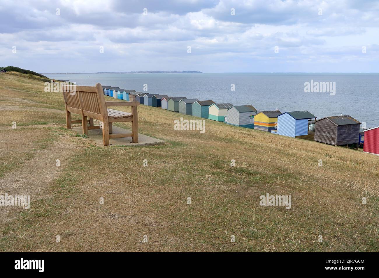 A wooden bench overlooking the colourful beach huts at Tankerton Stock ...
