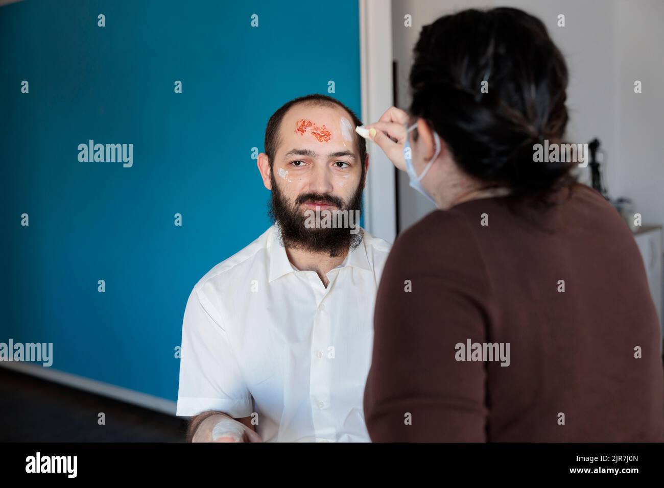 Makeup artist transforming man into zombie with special effects, blood ...