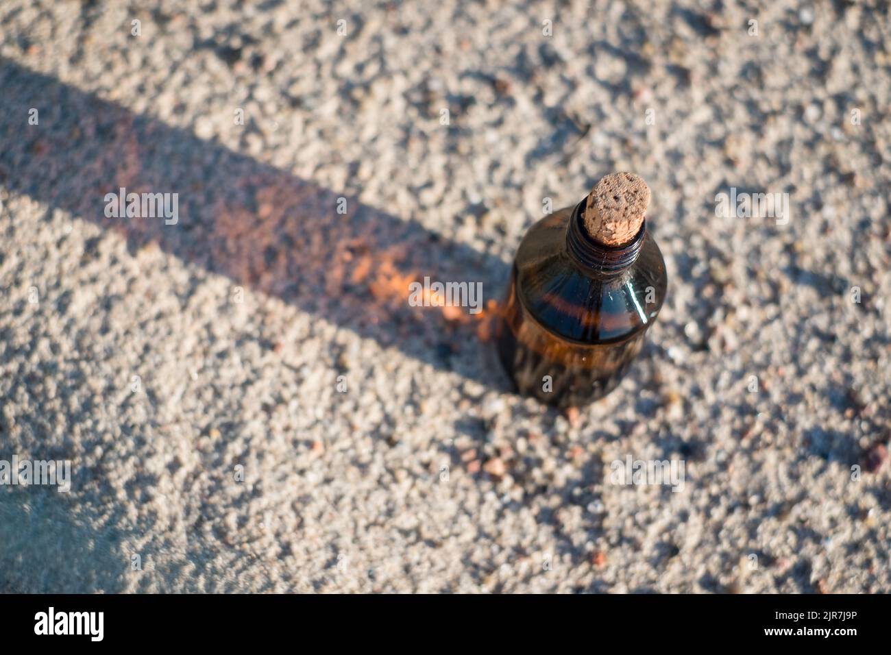 Essential oil bottle on a sandy beach. Little brown medicine bottle in ...