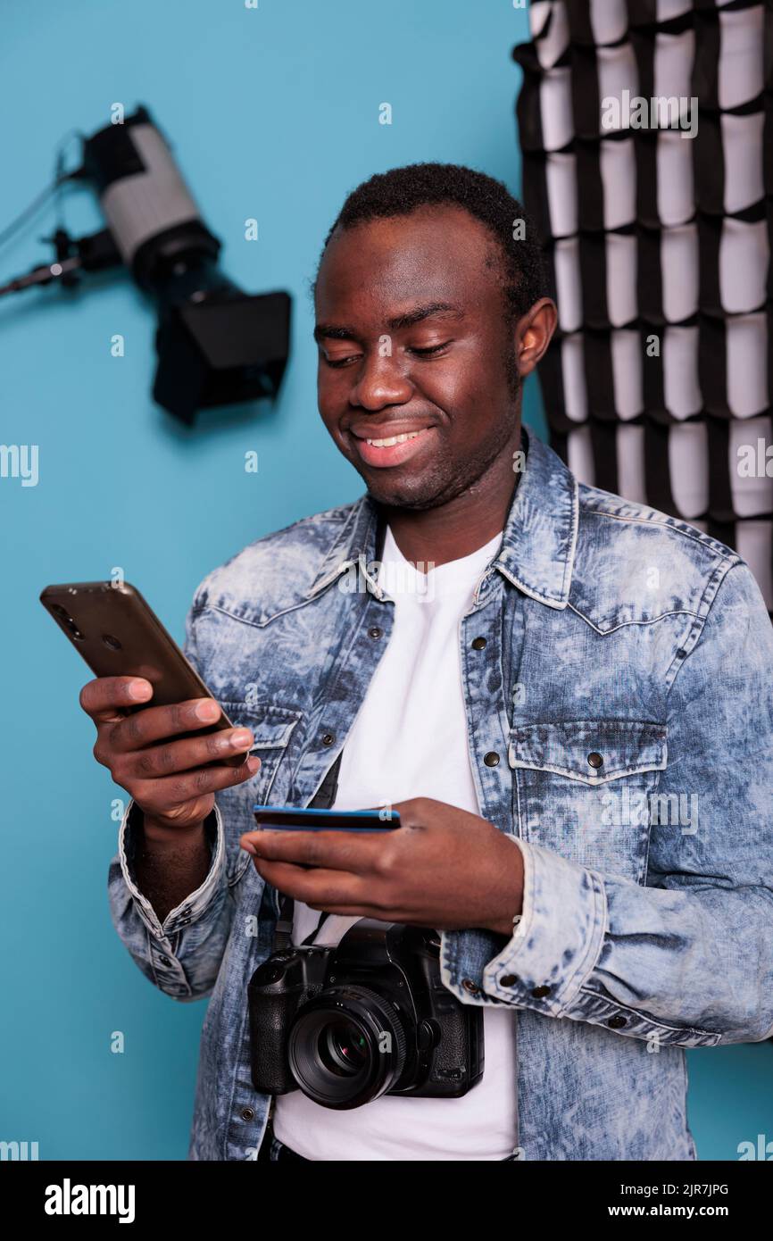 Studio producer making an online payment on smartphone with credit card ...