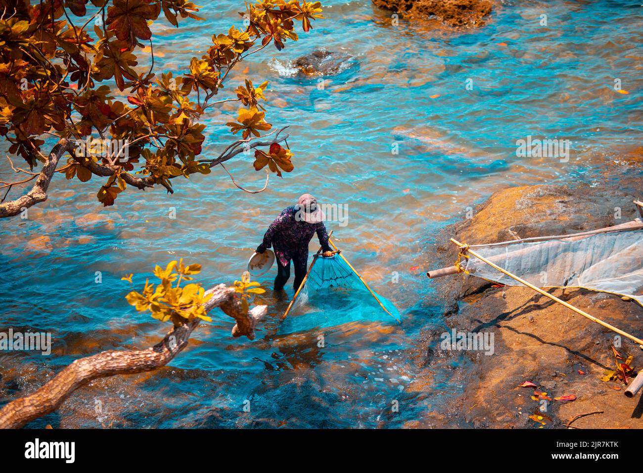 A fisherman using nets to catch fish on the shore in the Philippines ...