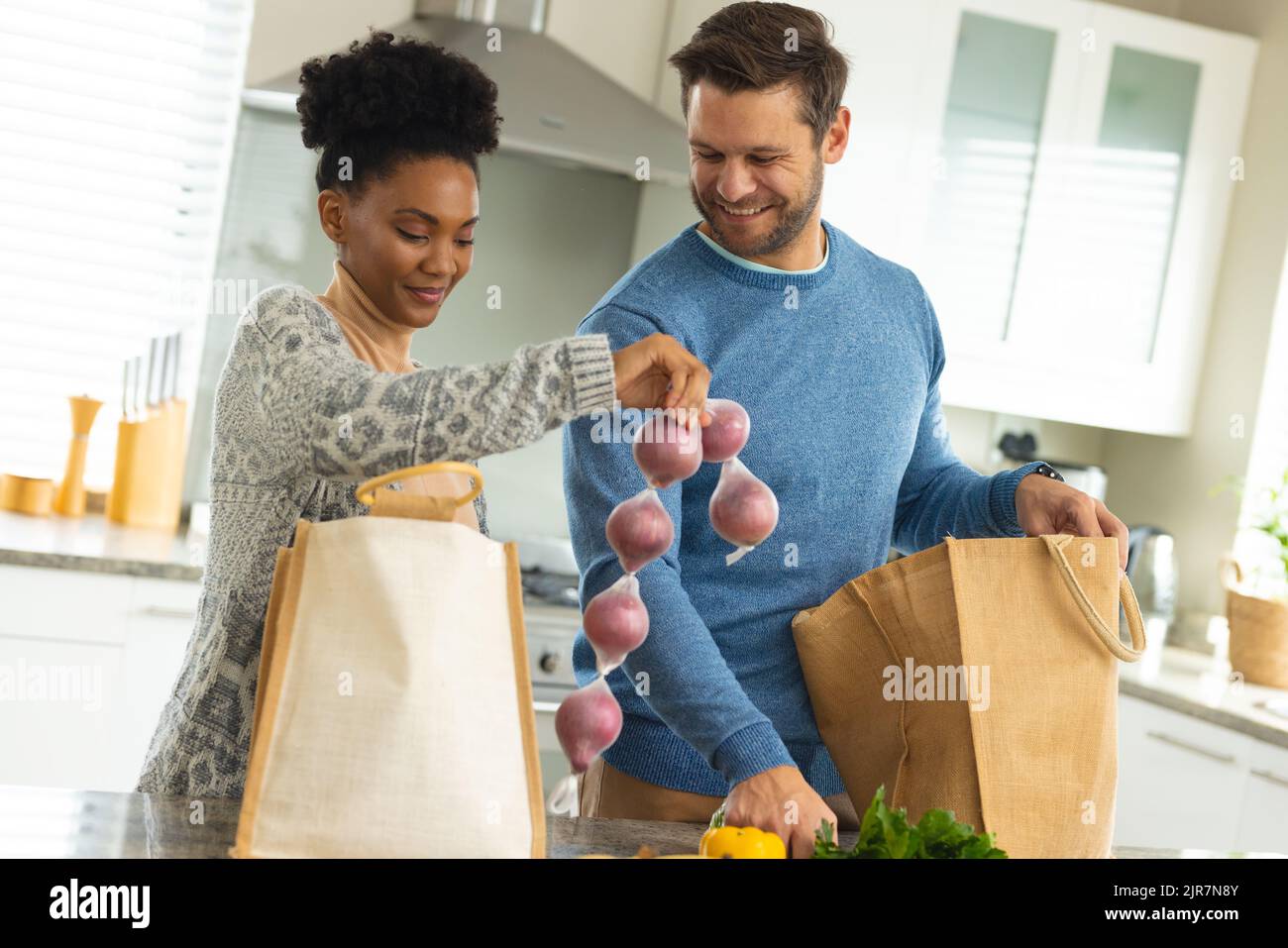 Image of happy diverse couple unpacking groceries in kitchen Stock ...