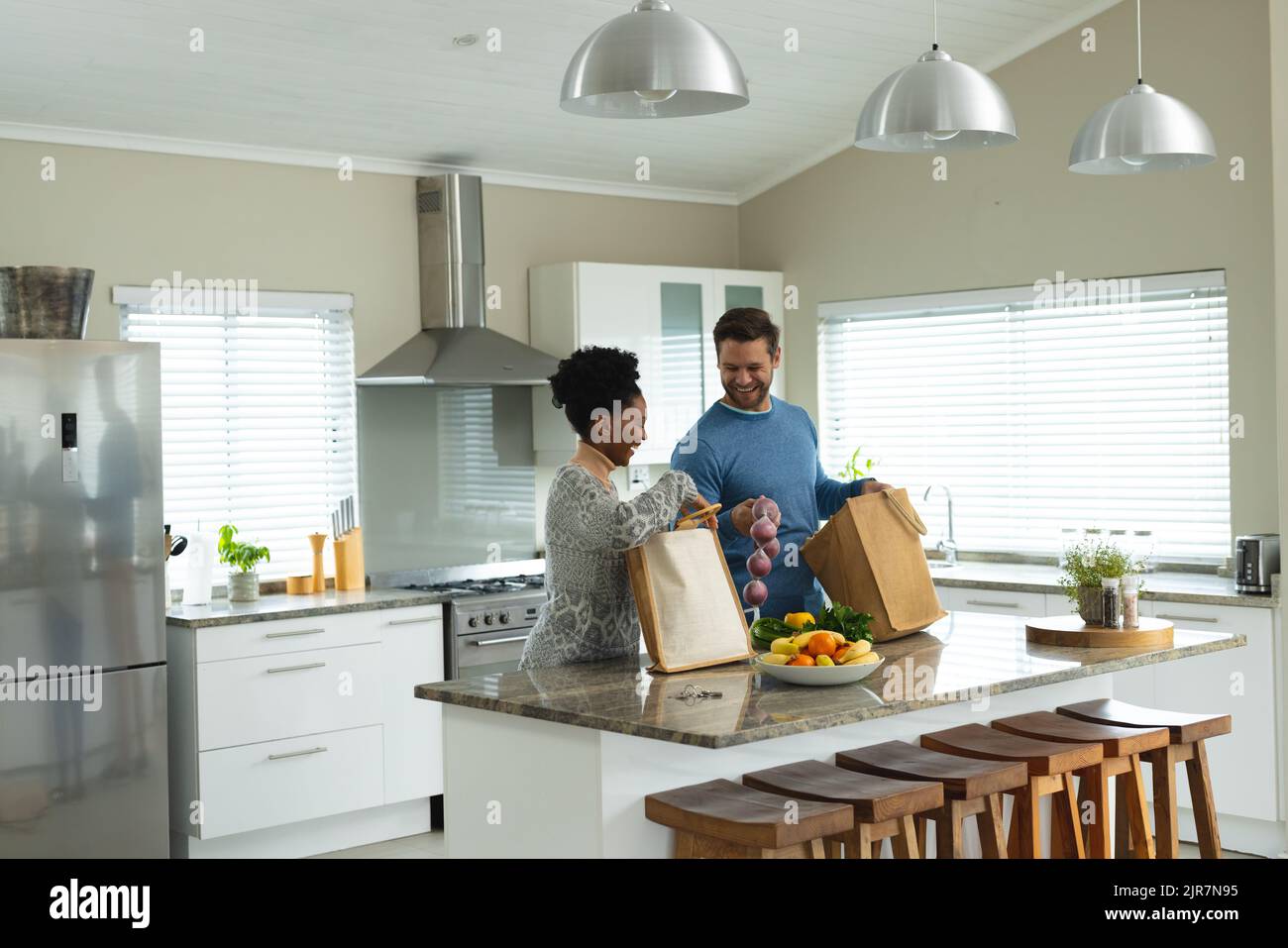 Image of happy diverse couple unpacking groceries in kitchen Stock ...