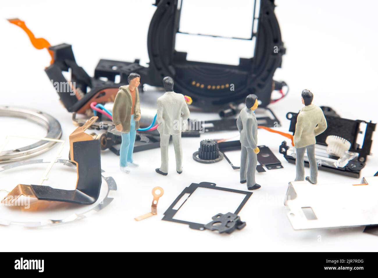 Miniature people. Business men stand near disassembled parts of an ...