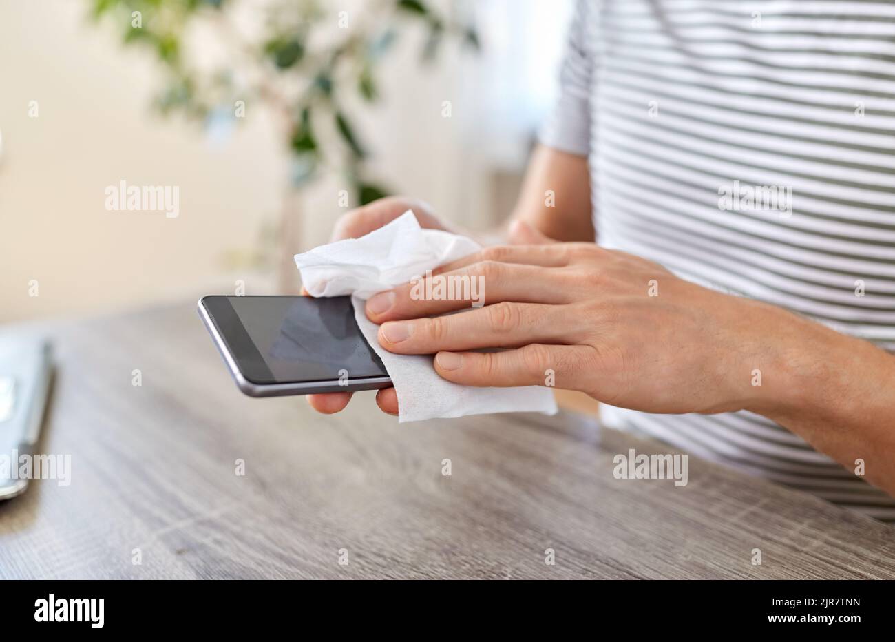 man cleaning phone with wet wipe at home office Stock Photo - Alamy
