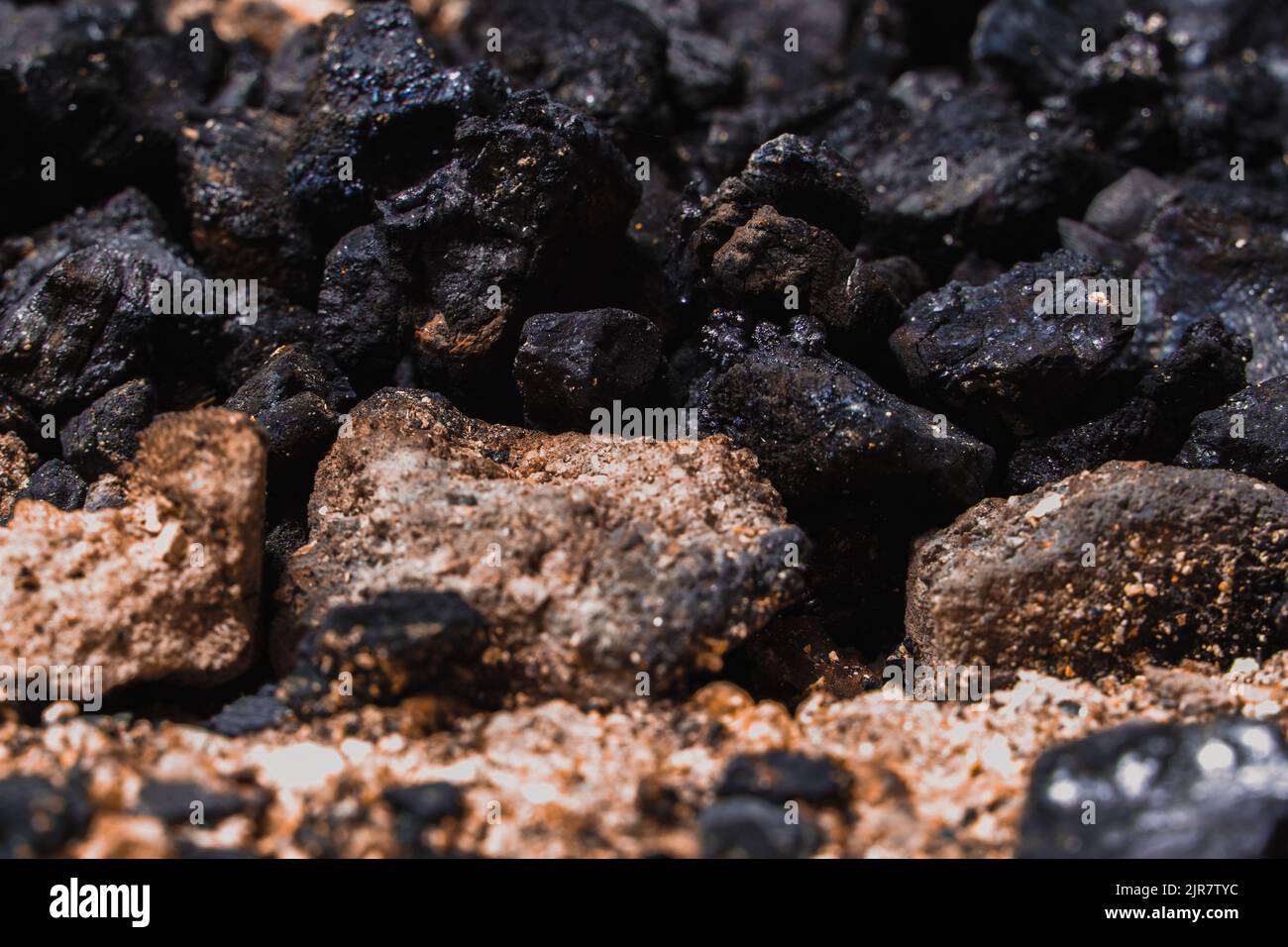 A closeup of chunks of coal on the ground after a volcanic eruption ...