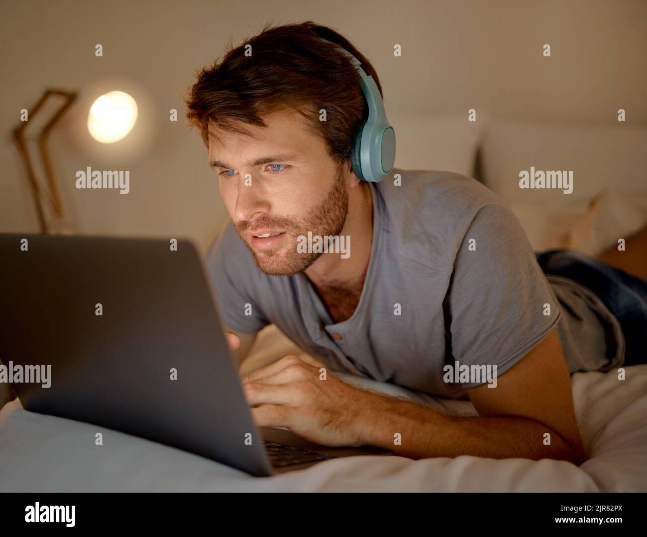 Online, laptop and late night stream or work in the bedroom. Man using ...