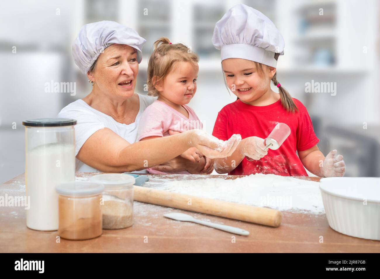 Grandmother with children prepare pastries and play with flour in the ...