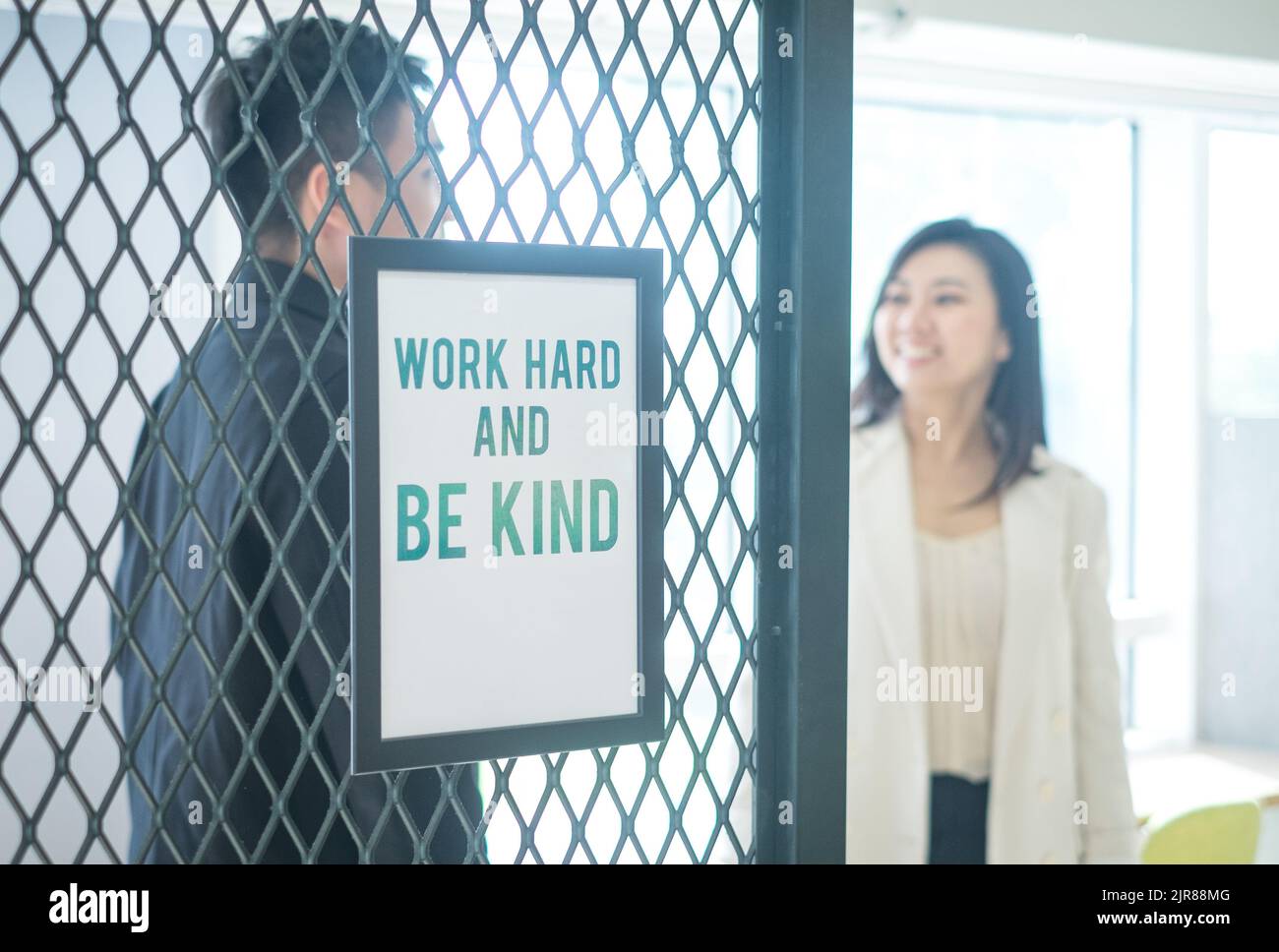 A sign in an office, Work hard and be kind. Office business people in ...