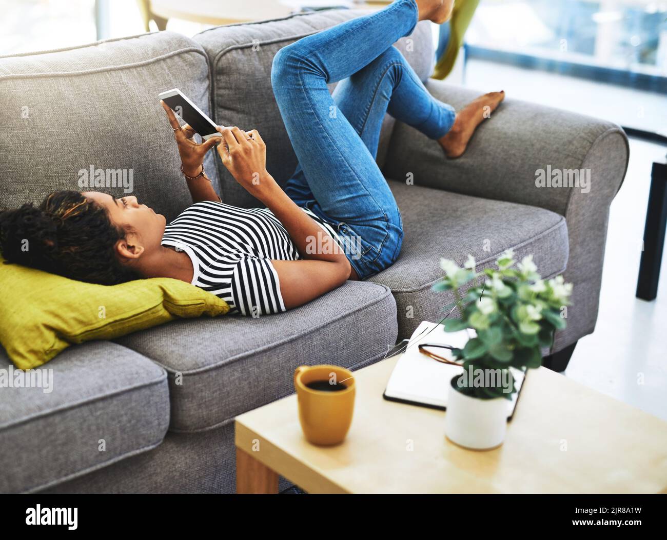 Texting all her friends. an attractive young woman relaxing at home on ...