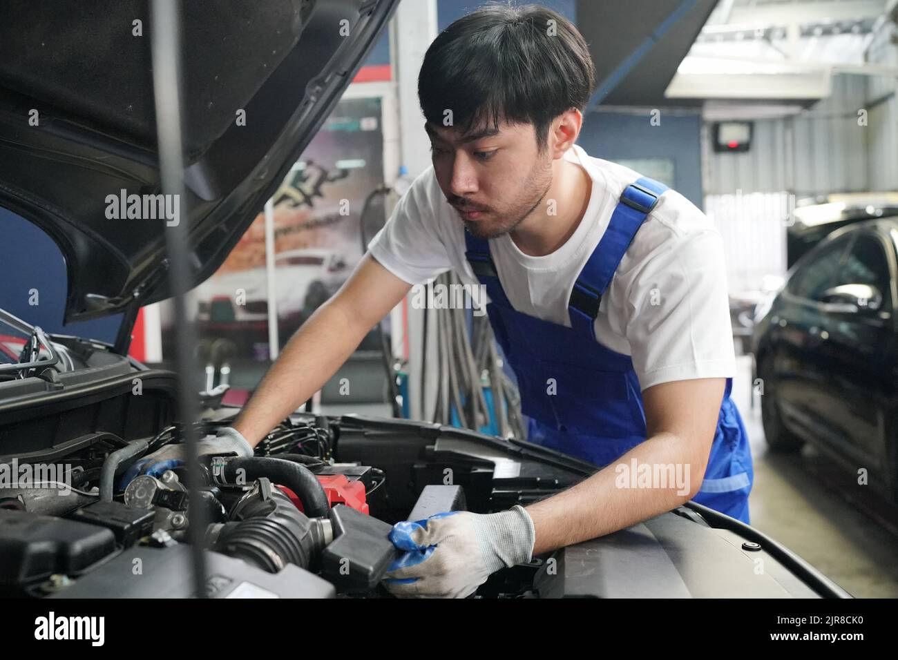 Male car operator wearing blue overalls,cap and gloves working under ...