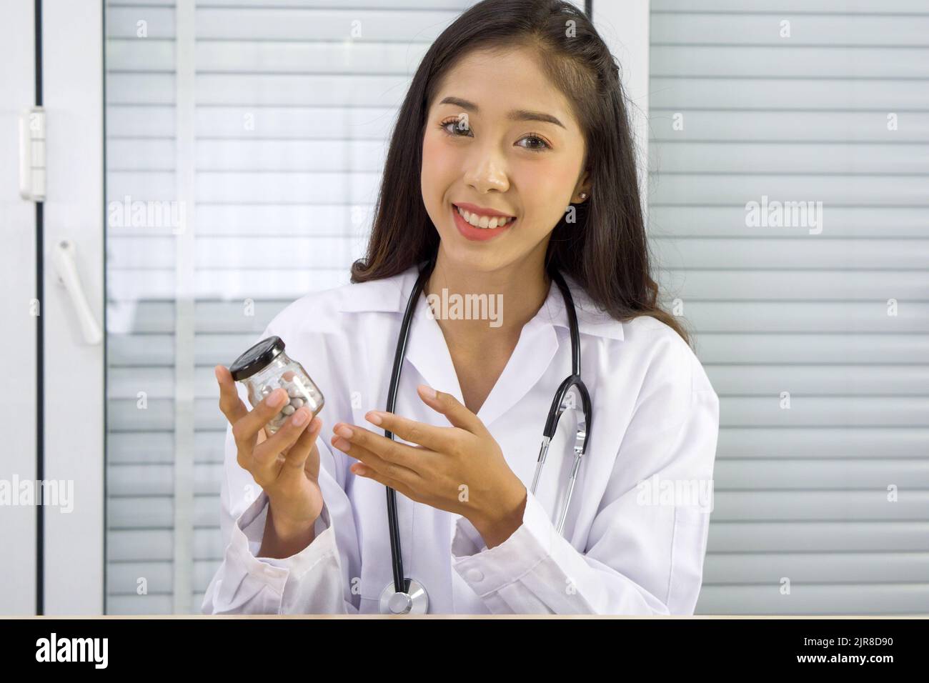 Young asian doctor in white gown and stethoscope holding medical ...