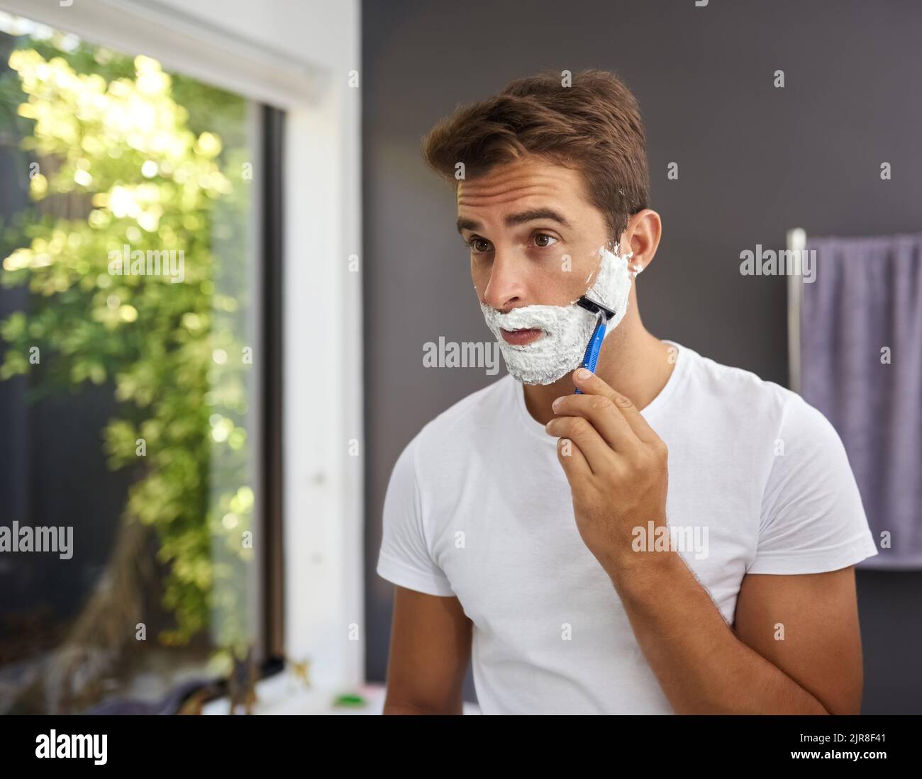 Time to say goodbye facial hair. a handsome man shaving his beard in ...