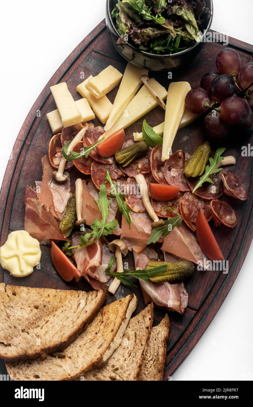 mixed cheese and cold cuts snack platter board on white background ...