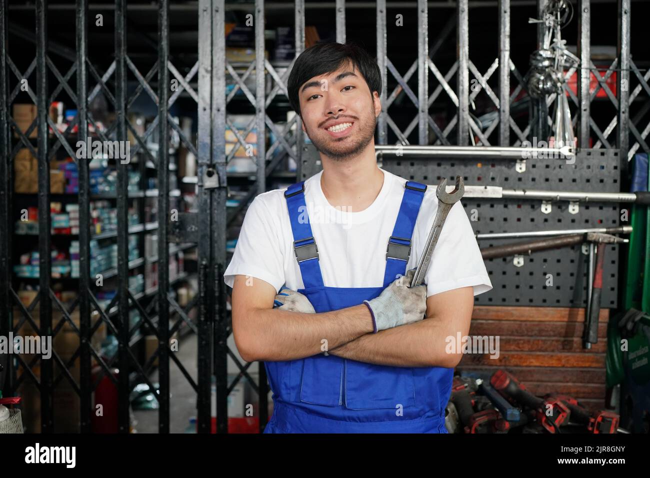 Male car operator wearing blue overalls,cap and gloves working under ...