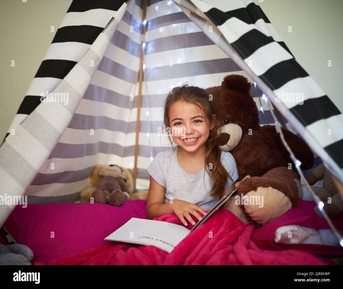 Its her own little reading nook. Portrait of a little girl reading a ...