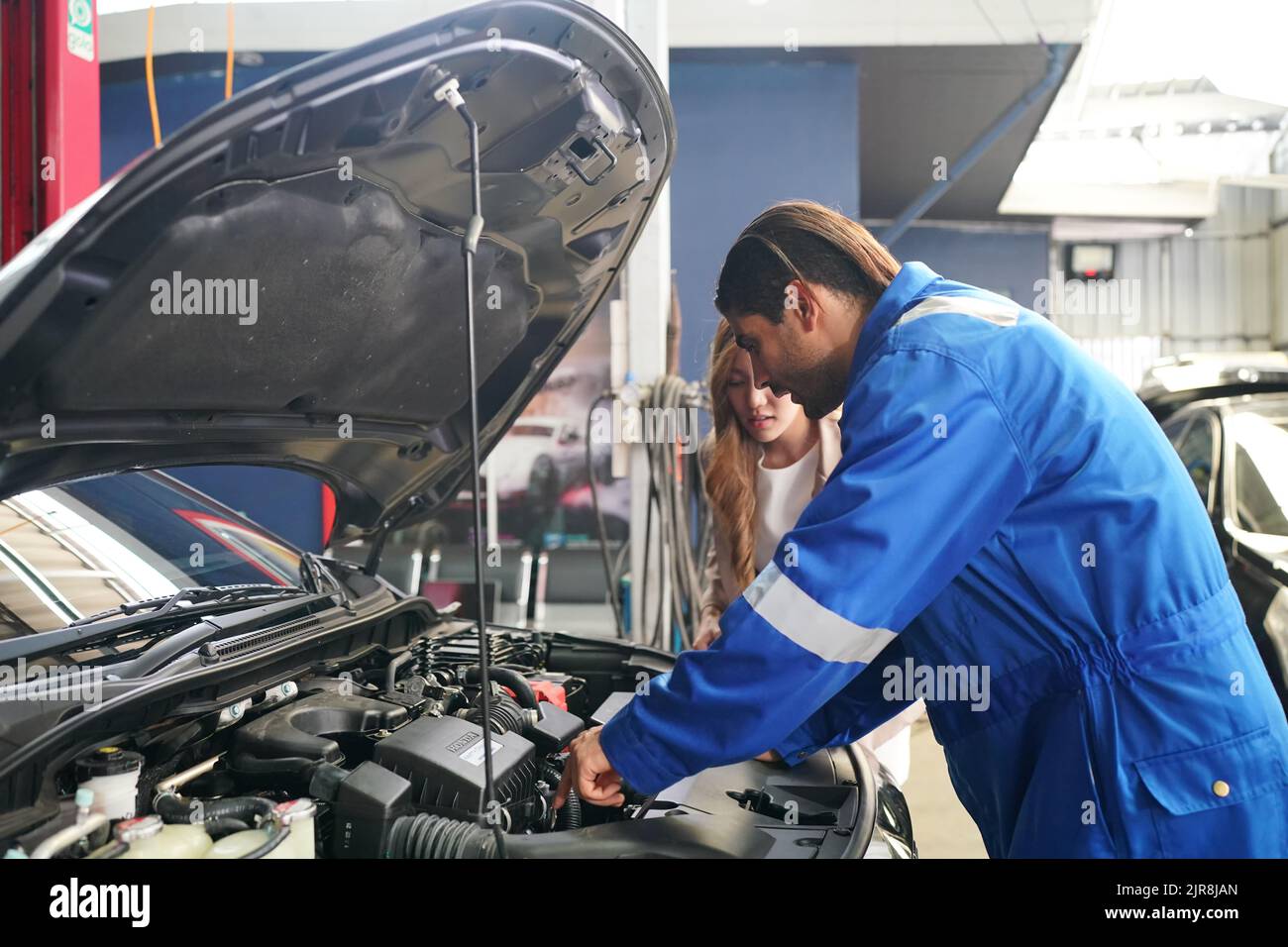 Male car operator wearing blue overalls,cap and gloves working under ...