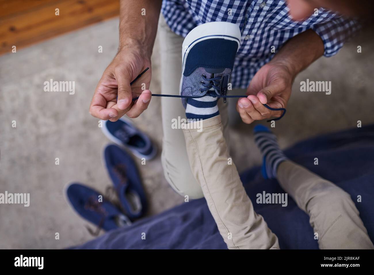 Helping him with his laces. High angle shot of an unrecognizable man ...